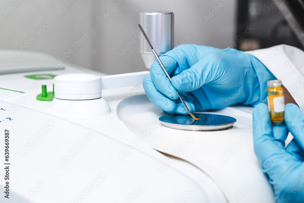 Hand of scientist using a stainless spatula to scoop sample solid from ...