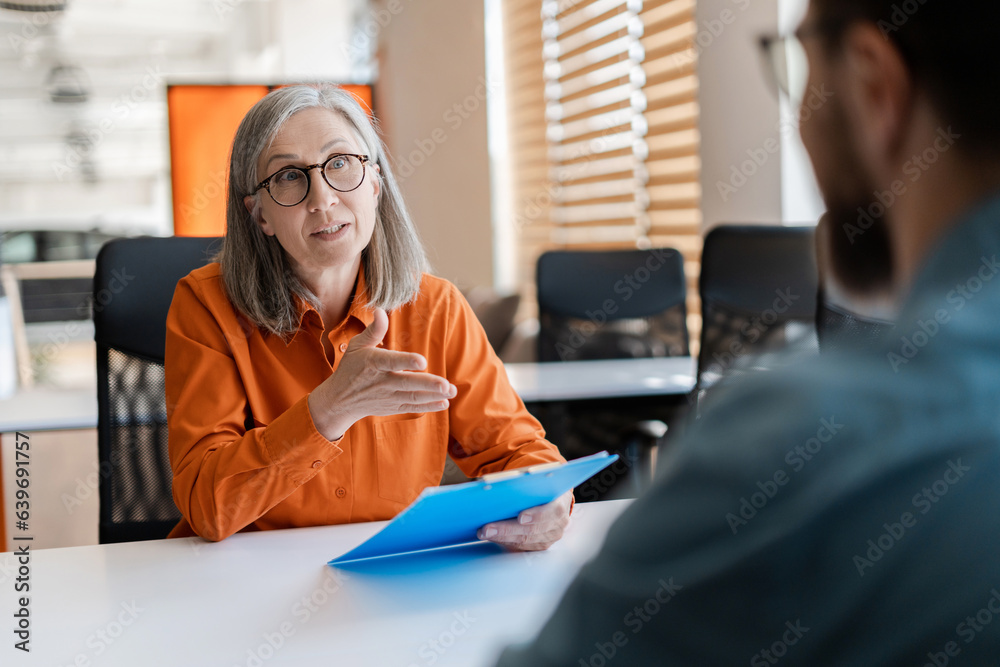 Senior business woman, employer holding resume listening young ...