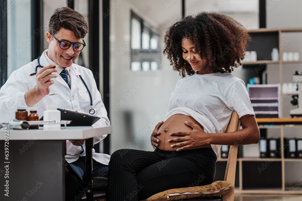 Male gynecologist doctor checking african american pregnant woman ...