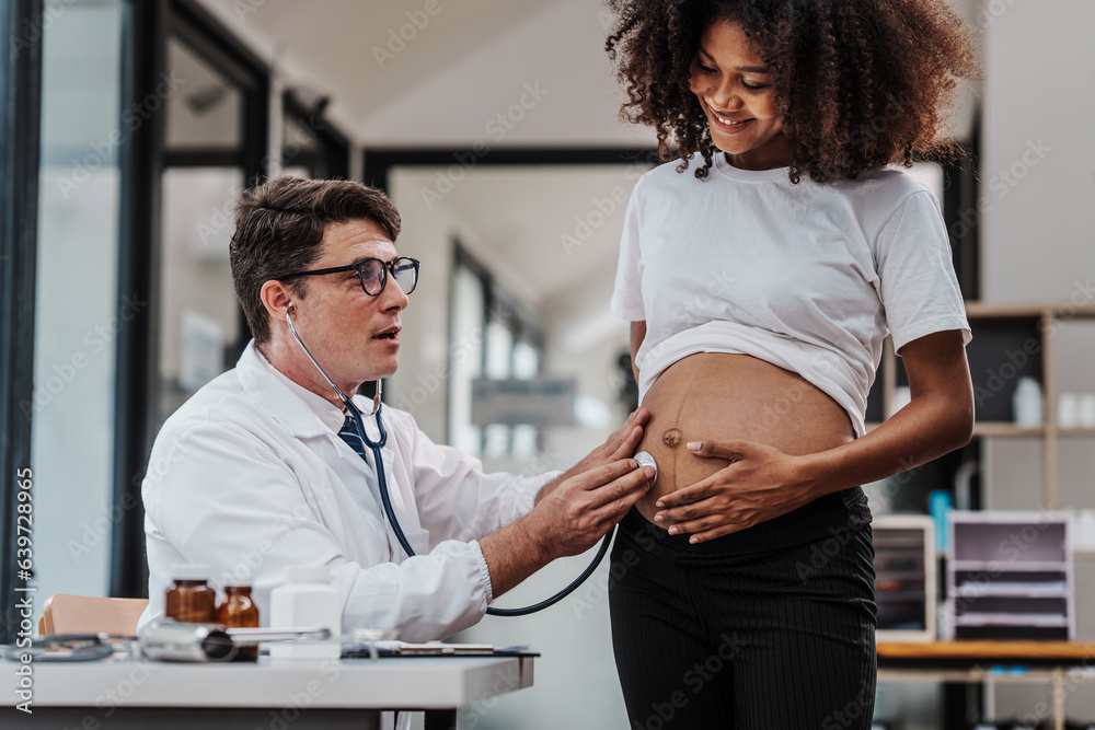 Male gynecologist doctor checking african american pregnant woman ...