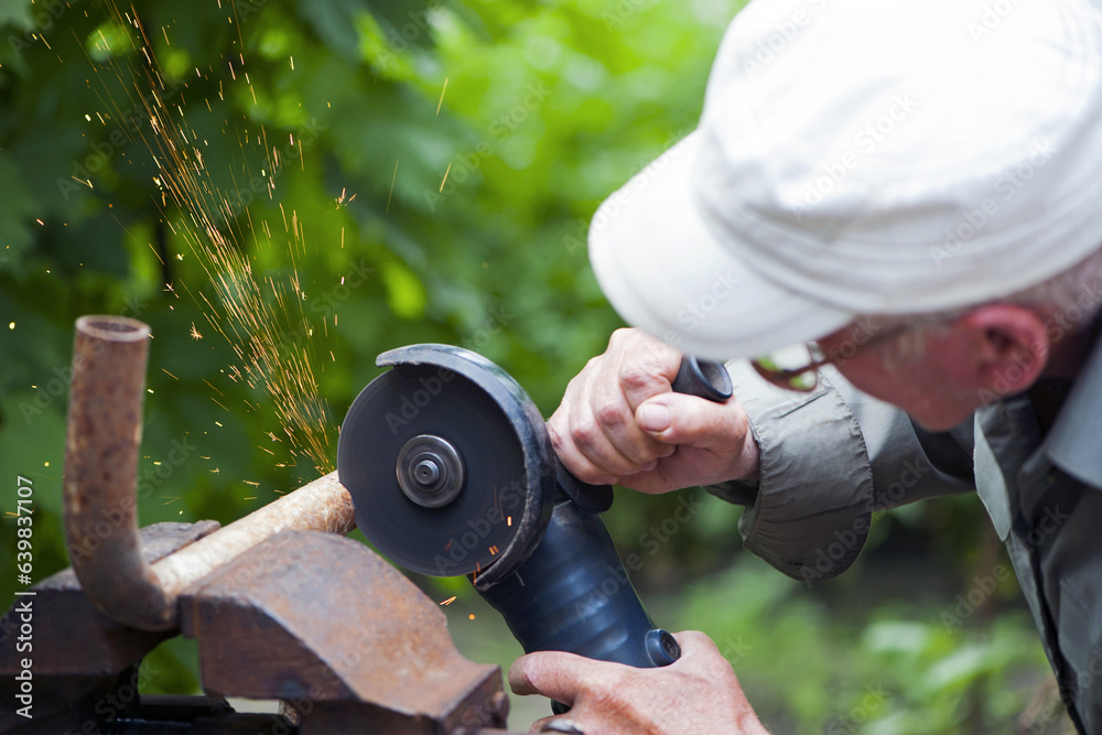 old man working. Cutting a metal pipe. spark. the pipe is clamped in a ...