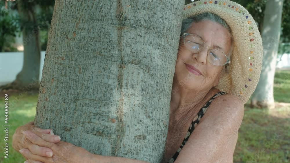 One old mature lady hugging a tree with love and feeling expression on ...
