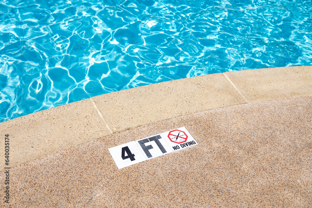 Edge of swimming pool with no diving warning sign and 4 foot depth ...