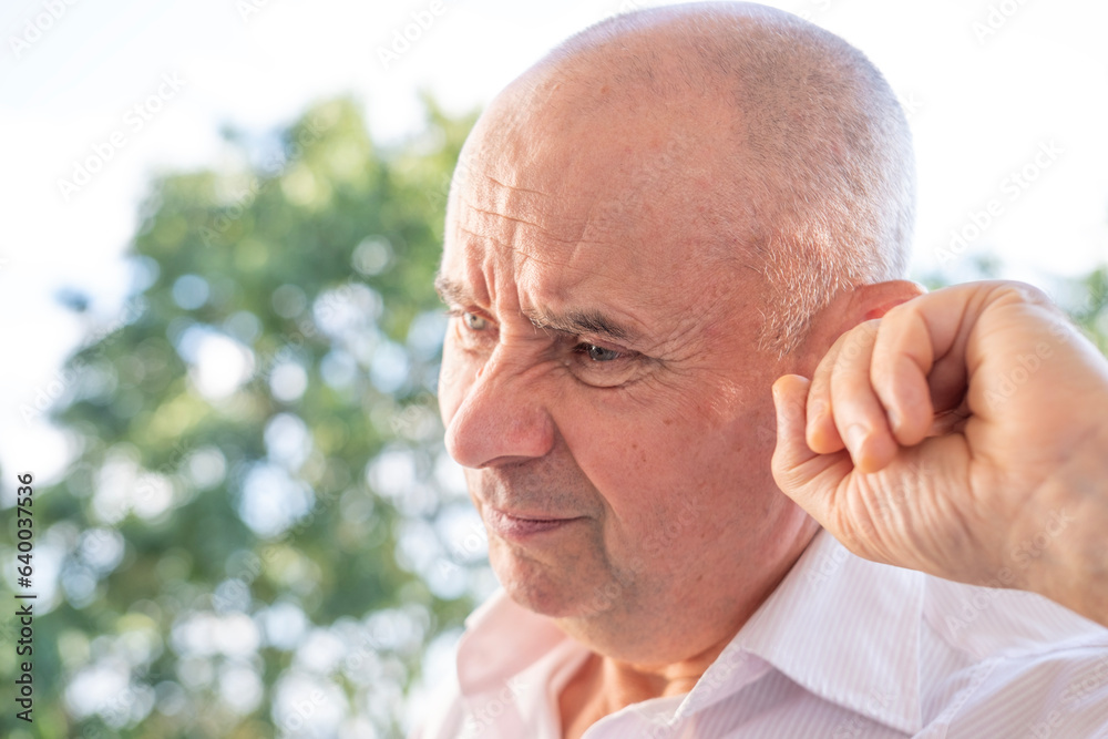senior, mature man 65 years old holds to ear, close up male face with ...