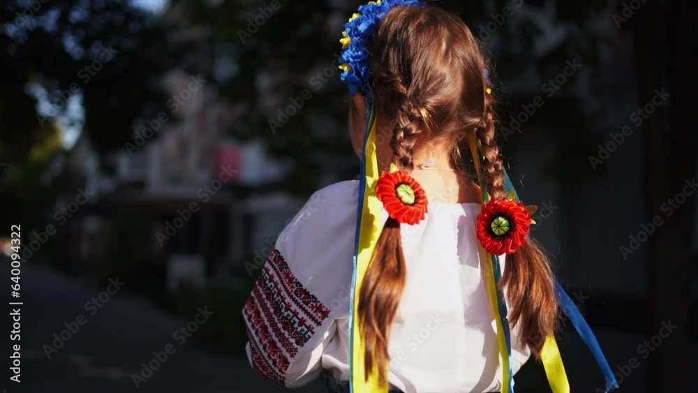 Child girl in Ukrainian traditional clothes and flower wreath is ...