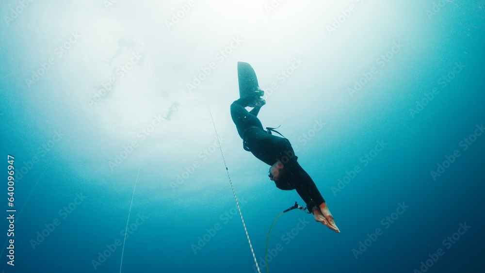 Freediving on the rope in a sea. Male freediver descends along the rope ...