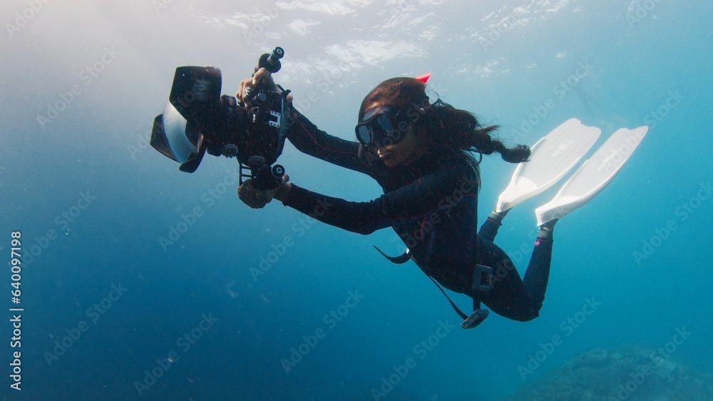 Poster Female Indian underwater photographer swims with big underwater ...