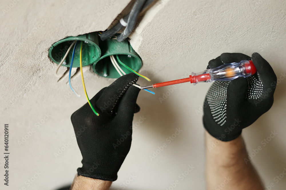 Cropped photo electrician male in protective gloves checks presence of ...