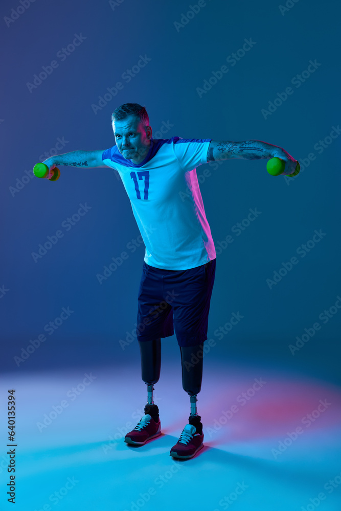 Young muscular man with prosthetic legs doing exercises in gym with ...