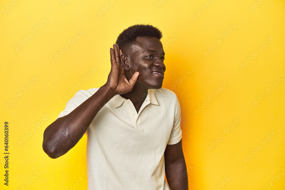 Stylish young African man on vibrant yellow studio background, trying ...