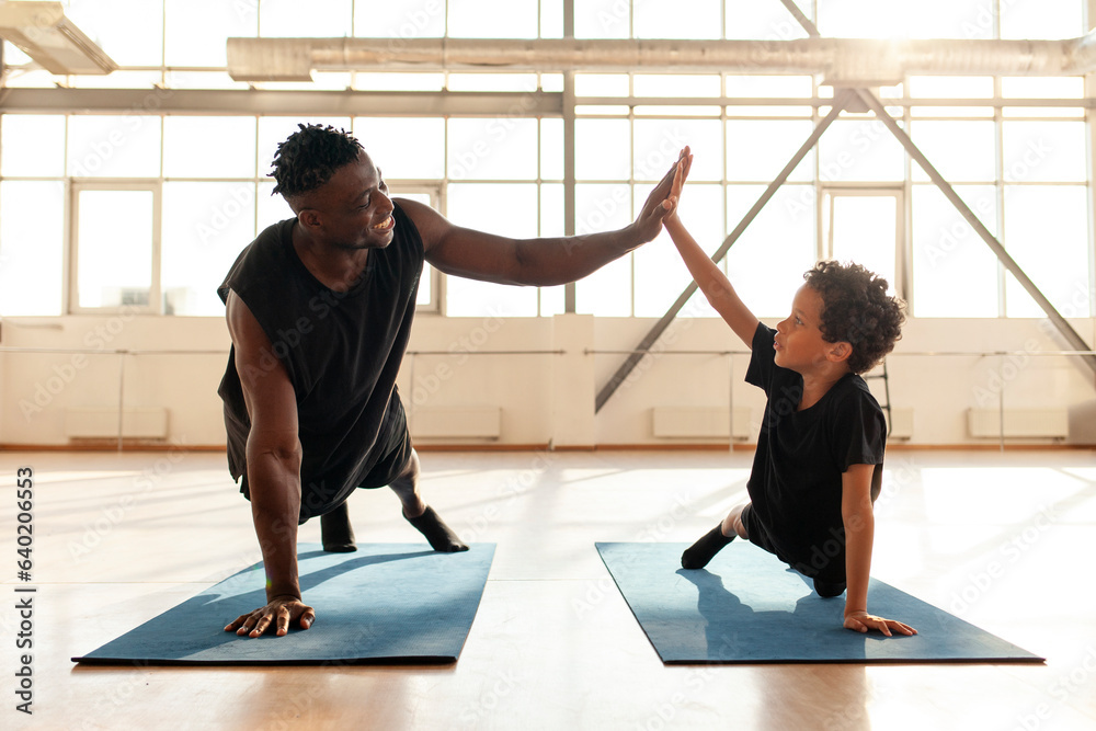 father and son do sports in the gym and give high five, african ...