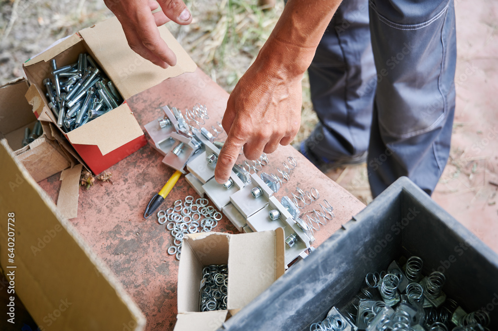 Close up of male worker standing by the table with various bolts ...