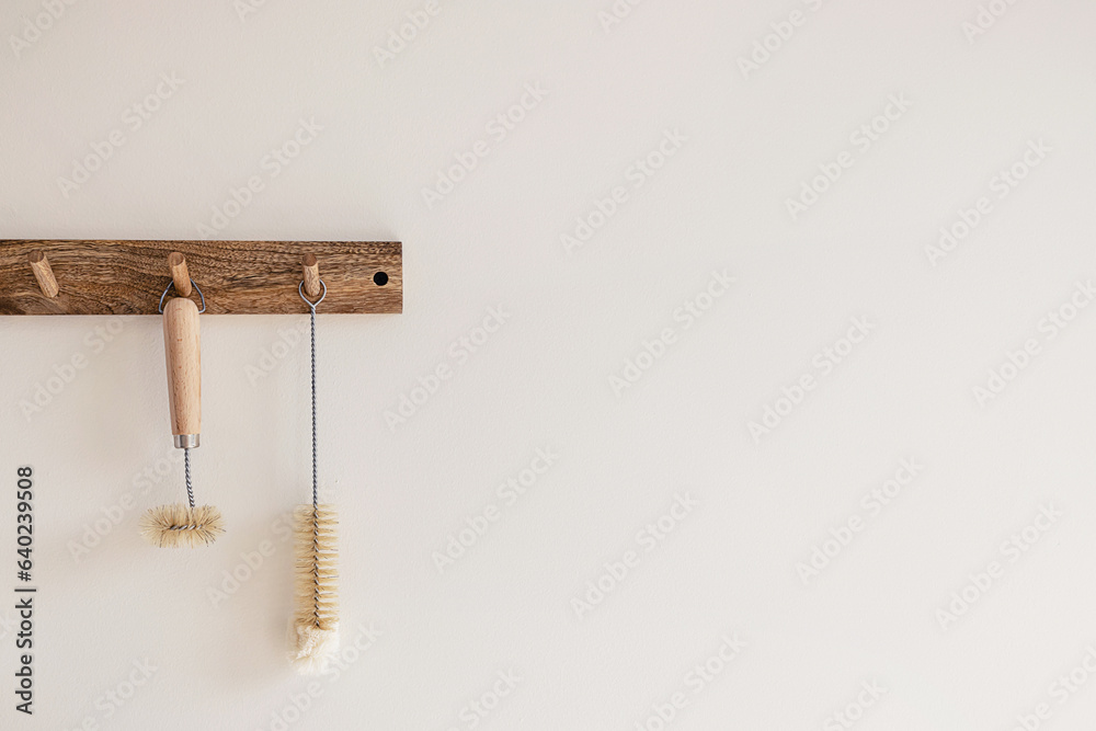 Wood hook rack with sustainable cleaning brush hanging on a white wall ...