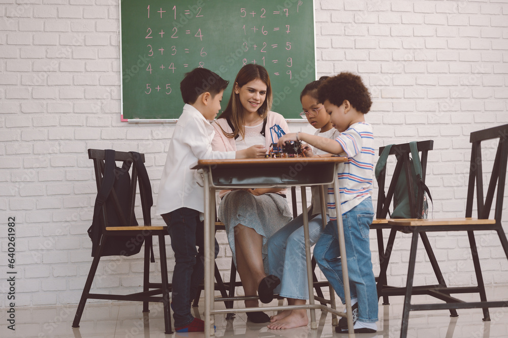 A teacher is teaching a group of children to sit and assemble robots ...