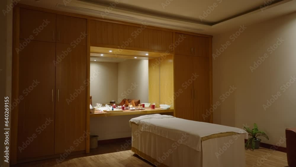 Massage bed in the middle of a spacious spa room with big wall mirror ...