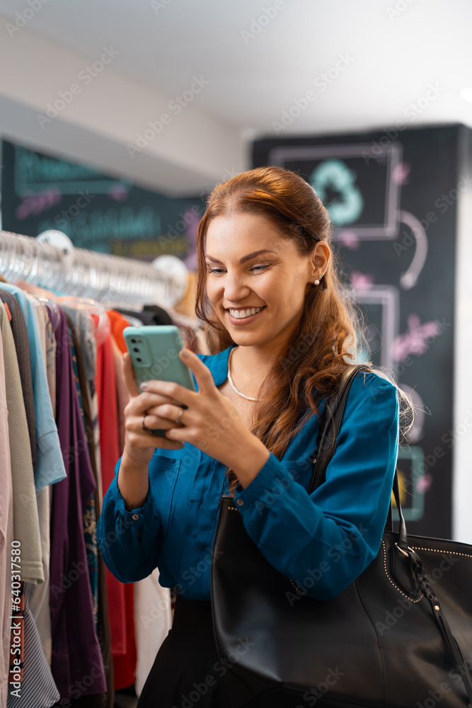 Checking mobile phone at thrift store. Female customer shopping ...