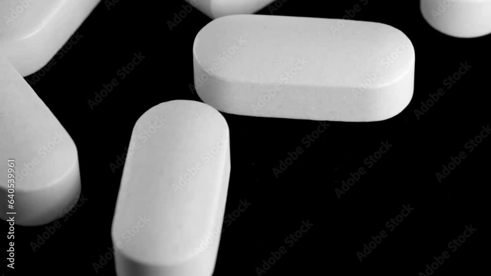 White oblong pills tracking shot close-up. Dependence and drug ...