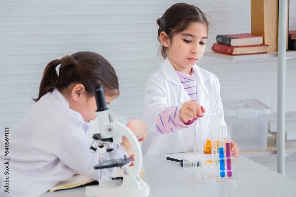 Group of sibling primary school students wearing lab coats having fun ...