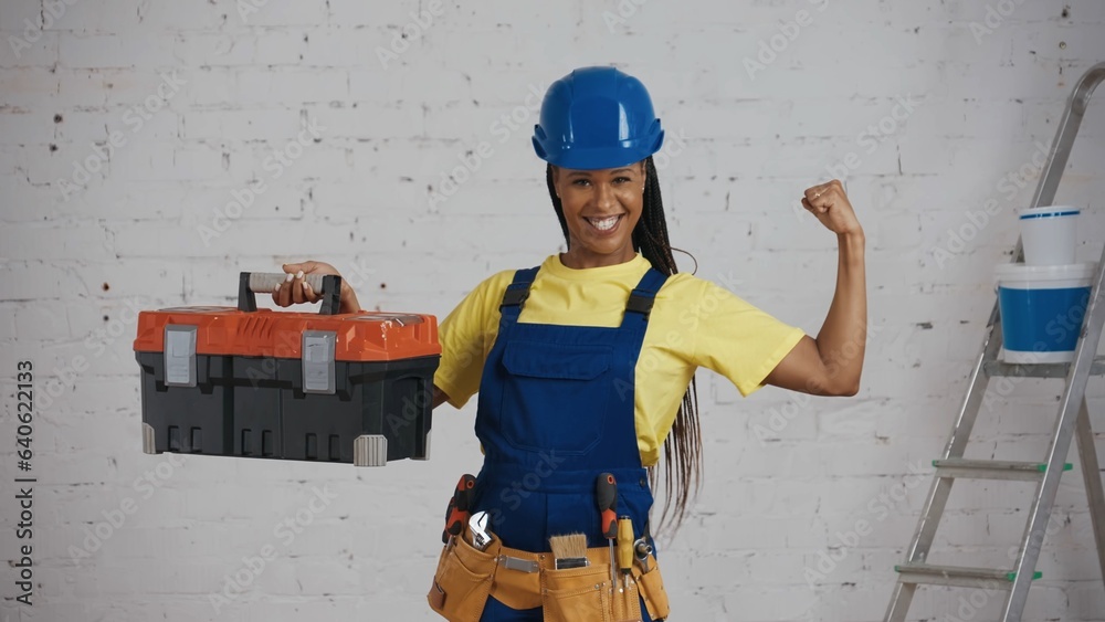 Medium shot of a dark-skinned young female construction worker standing ...