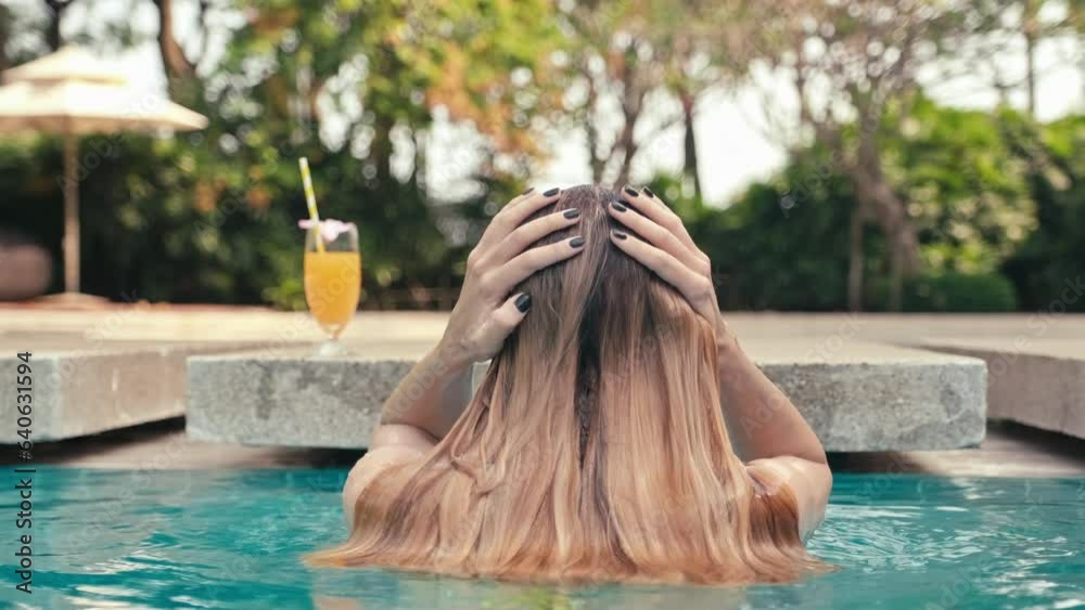 Back view of woman emerging from under water while being in swimming ...