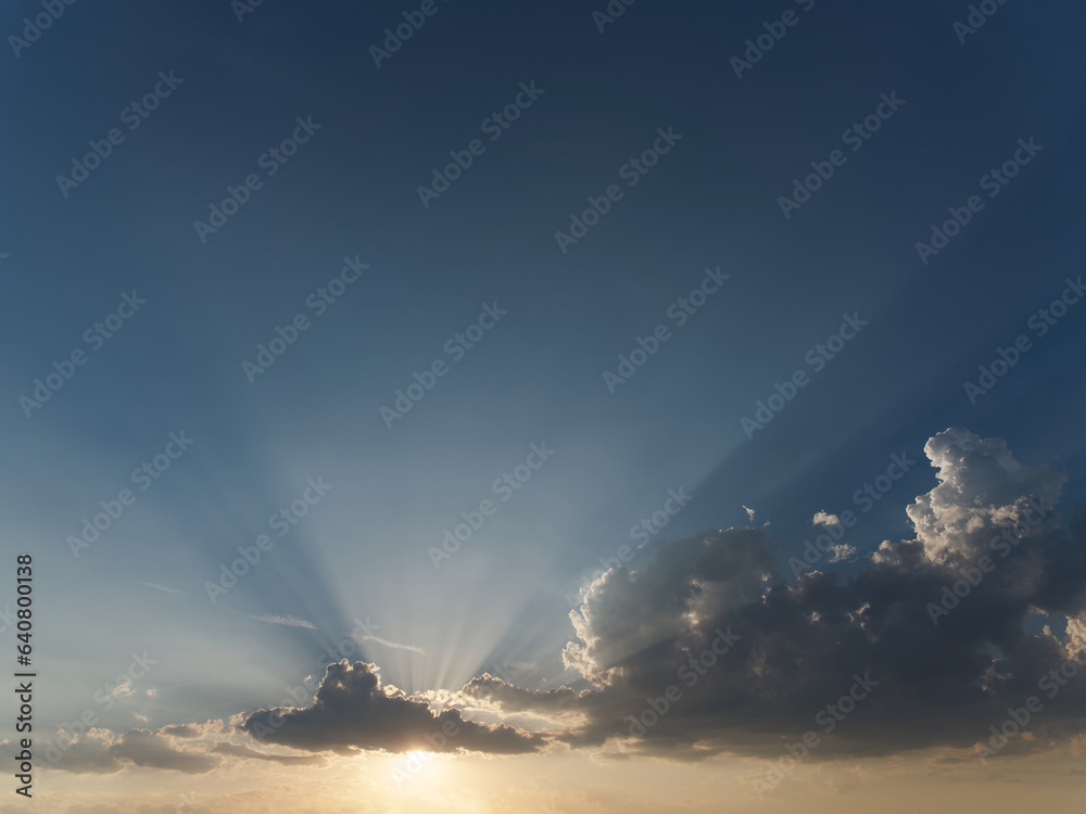 Sunset sky colors with god rays, high contrast with sun just below a ...