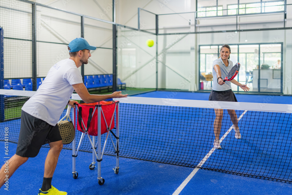 Elevating skills in indoor Padel training. Coach partners with female ...