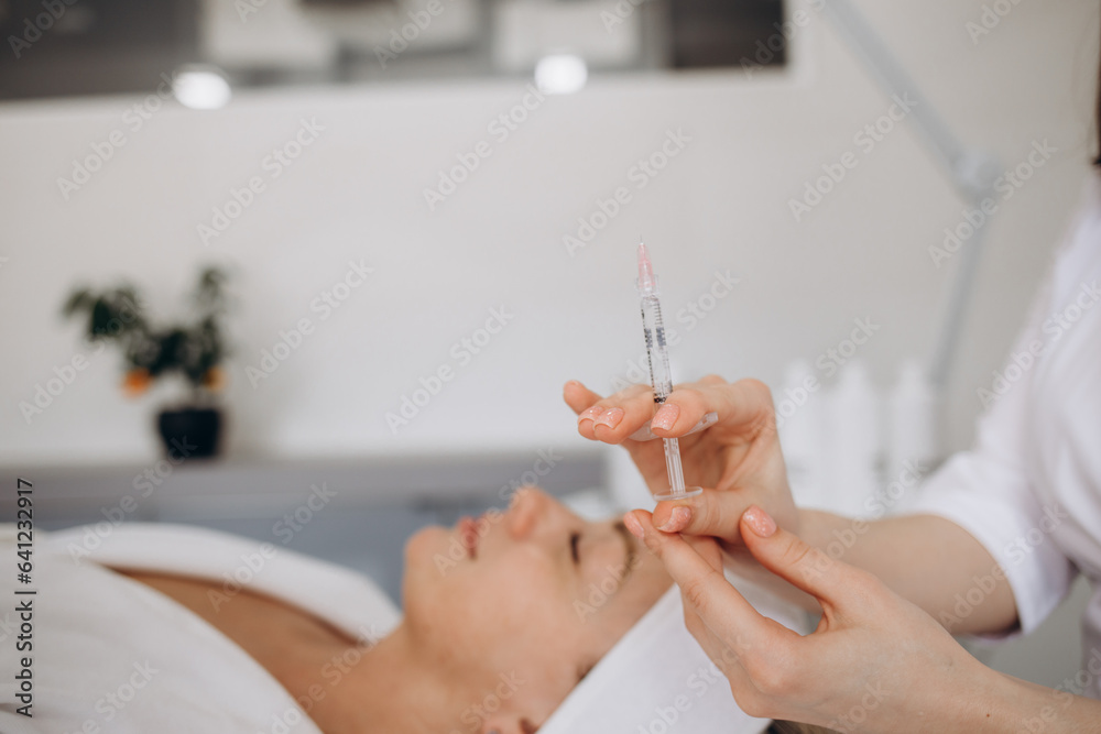 Young caucasian woman getting botox cosmetic injection in a forehead ...