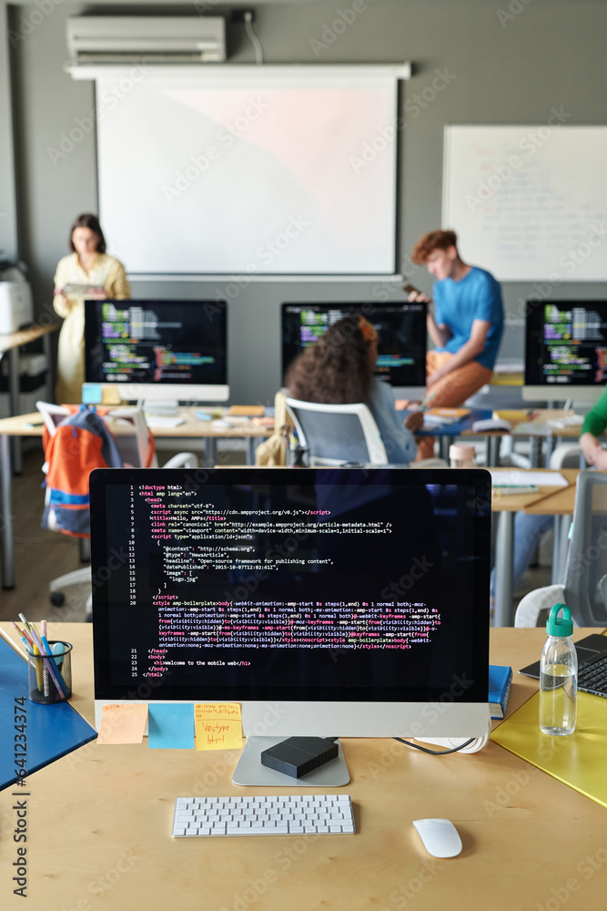 Vertical image of computer with codes on monitor standing on desk in ...