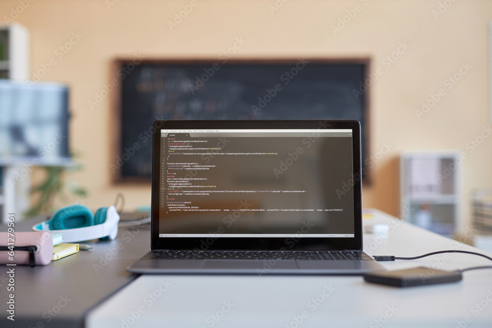 Laptop with coded data on screen standing on desk with headphones and ...