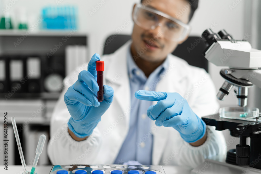 Doctor taking a blood sample tube from a rack with machines of analysis ...