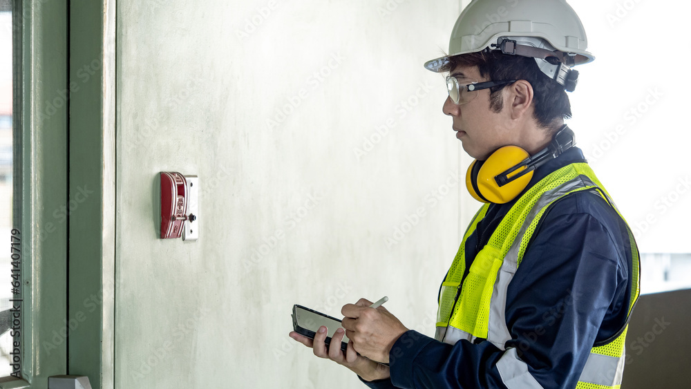 Building inspector man using digital tablet checking wall mounted fire ...