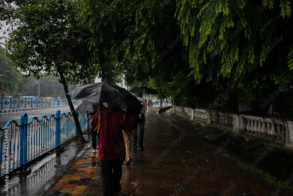 people walking with umbrella on a rain wet foot path and during monsoon ...