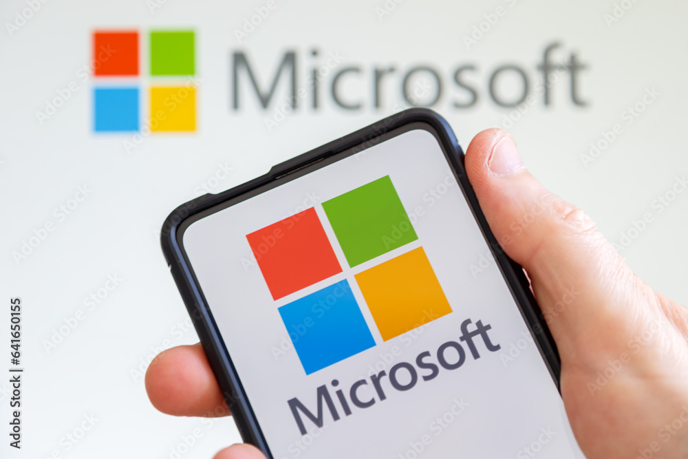 Hand holding a mobile phone with Microsoft logo of the software company ...