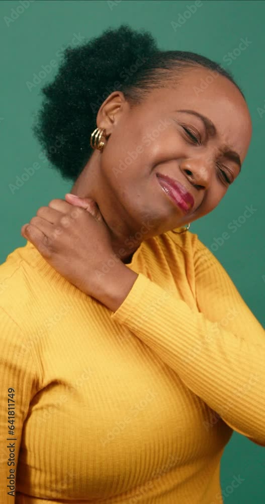 Young Black woman rubs neck in pain, muscle ache, green studio ...