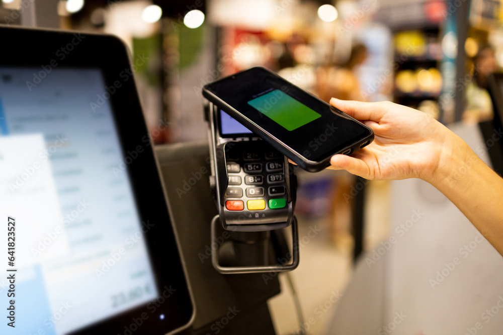 Crop person paying with smartphone in supermarket Stock Photo | Adobe Stock