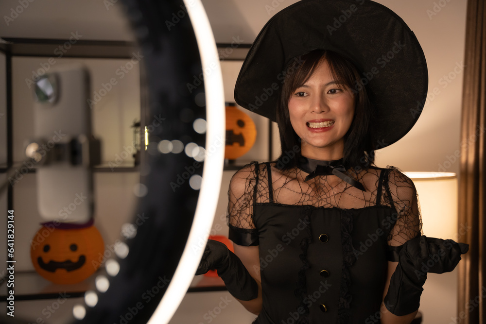 Female influencer wearing witch costume and live streaming at home. She ...
