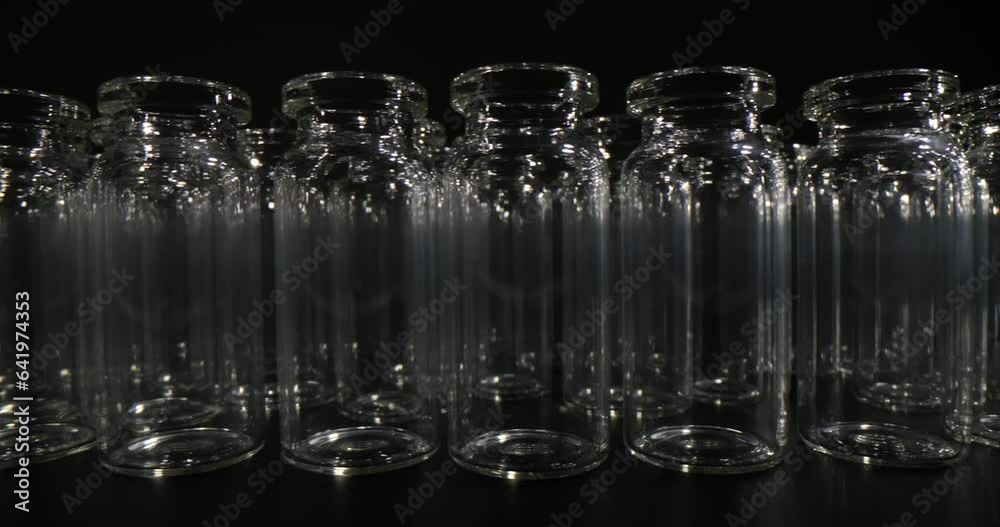 Empty glass vials for vaccines in rows on black surface in dark room ...