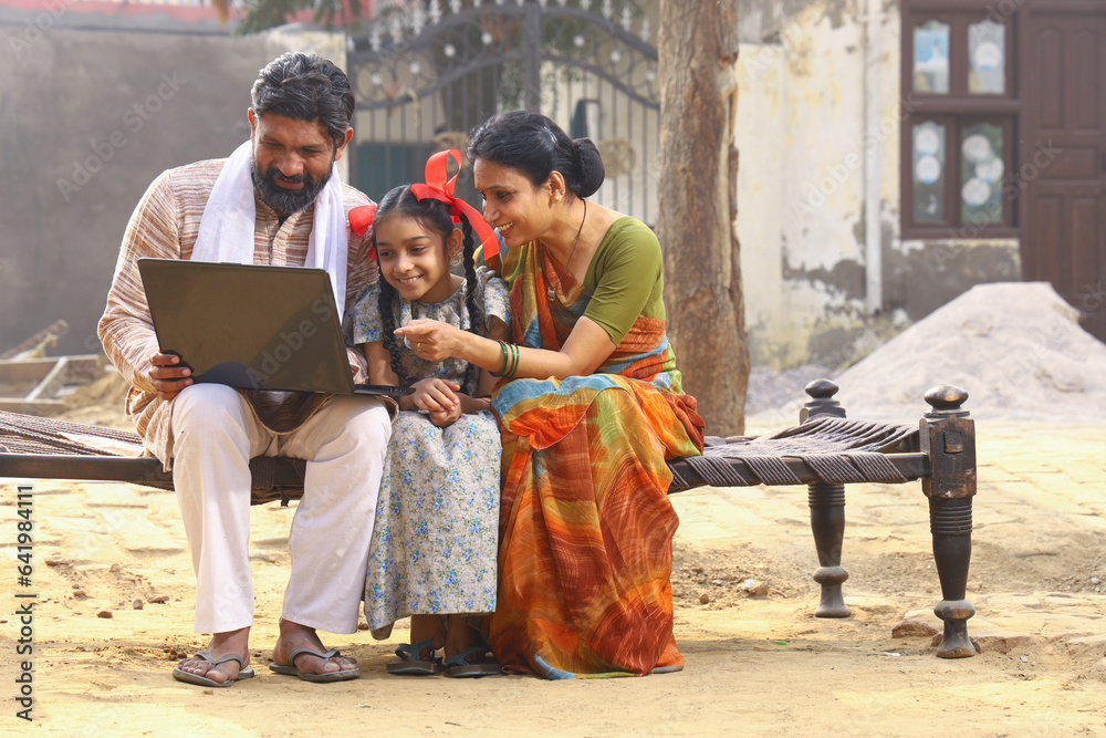 Happy Indian Rural family sitting on cot outside with girl child ...