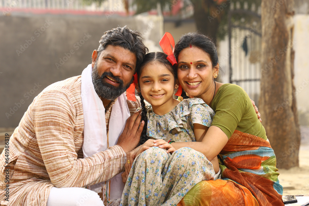 Happy rural Indian family sitting together outside their cottage in day ...