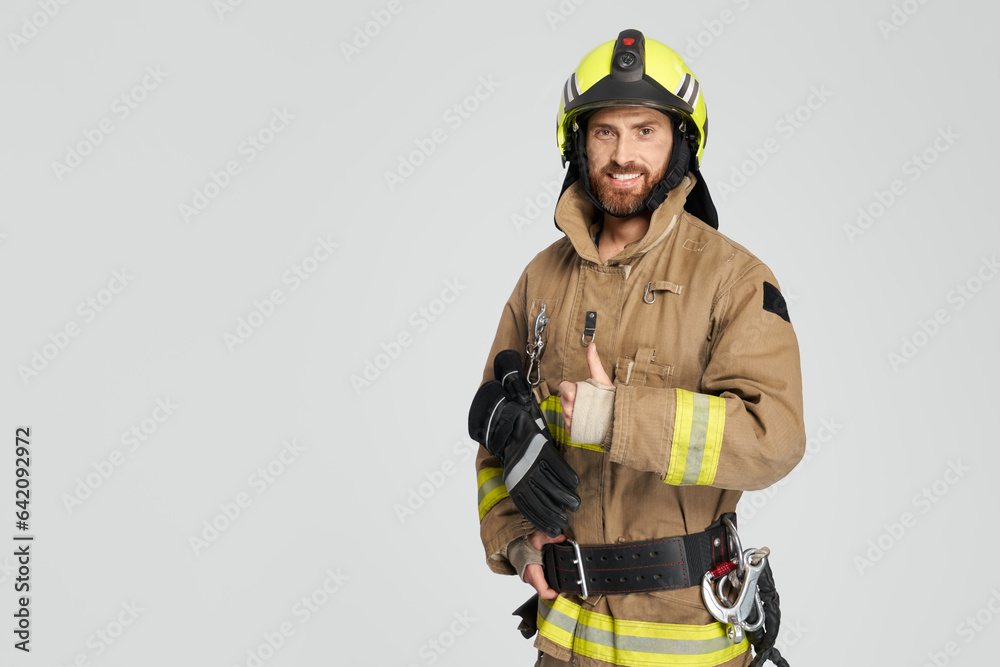 Happy caucasian firefighter in uniform showing thumb up in studio ...