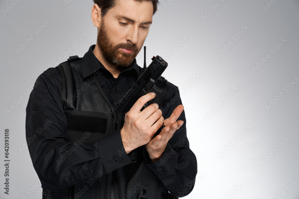 Focused dark-haired officer reloading weapon, getting ready to shoot ...