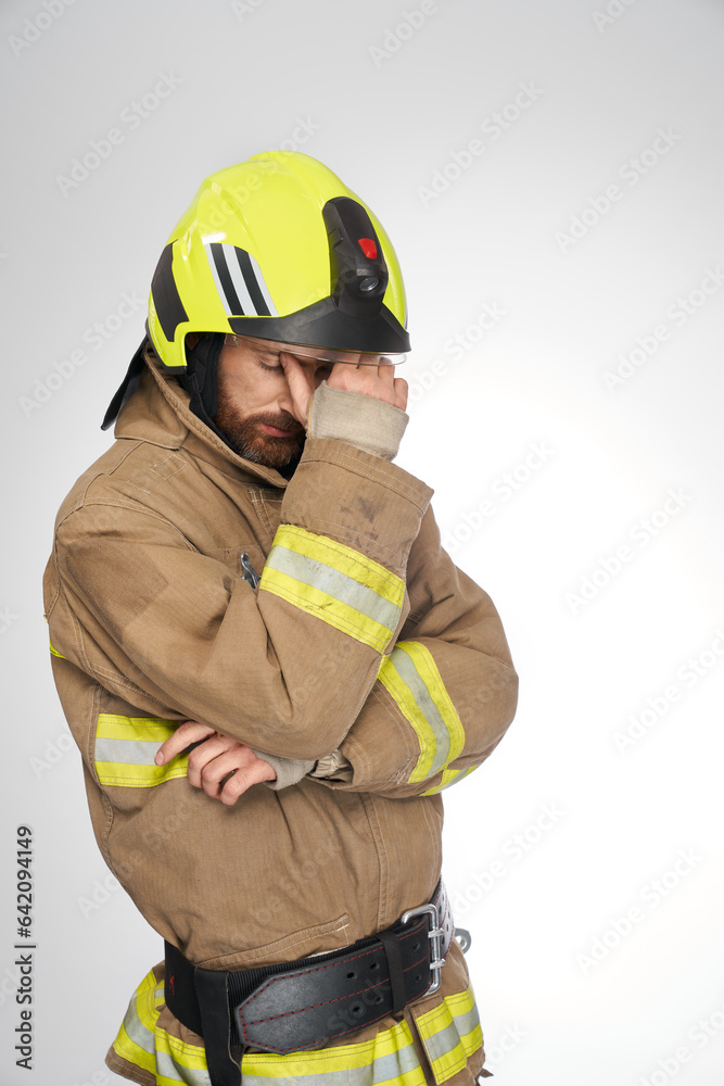 Sad, exhausted firefighter in uniform tiredly rubbing forehead in ...