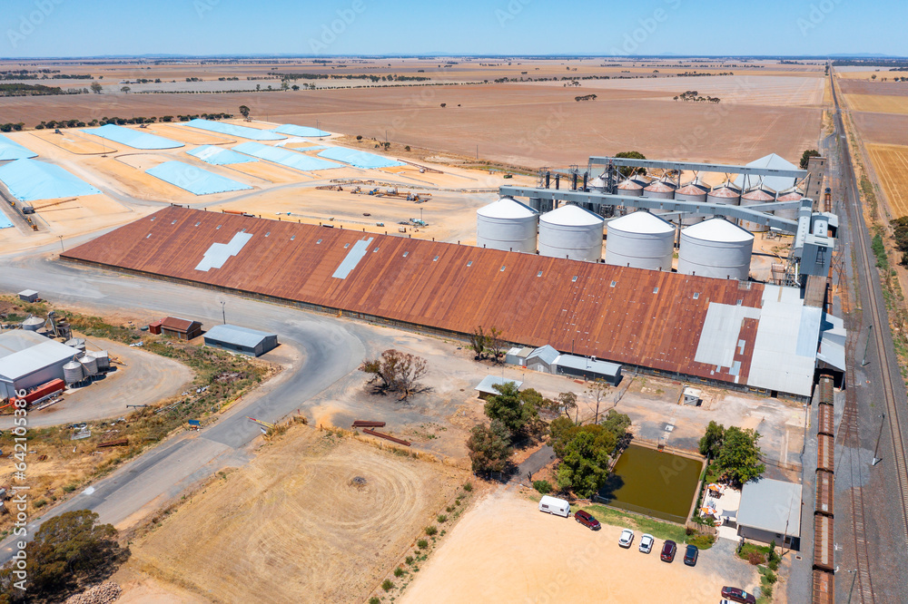 Aerial view of a long grain shed alongside silos and grain pits in a ...