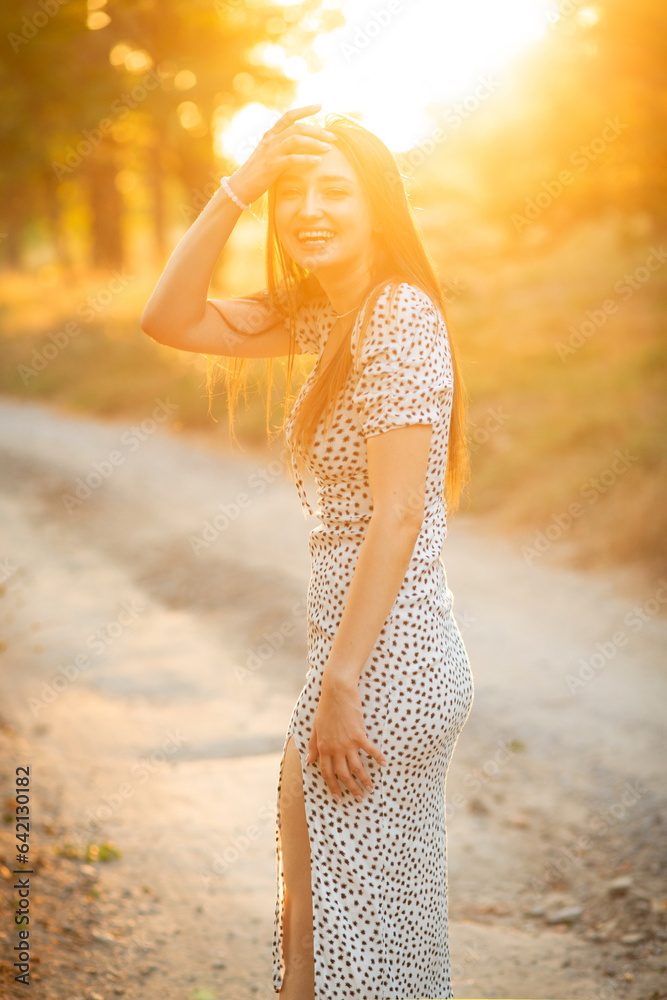cute smiling girl lit by warm sunlight on a path looking at you, young ...