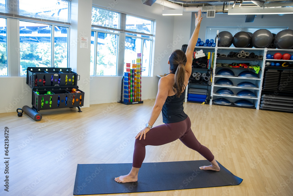 Strong woman practicing yoga with stretches and balanced poses in gym ...