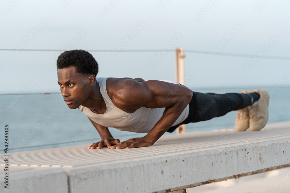 Strong black man doing plank exercise on parapet Stock Photo | Adobe Stock