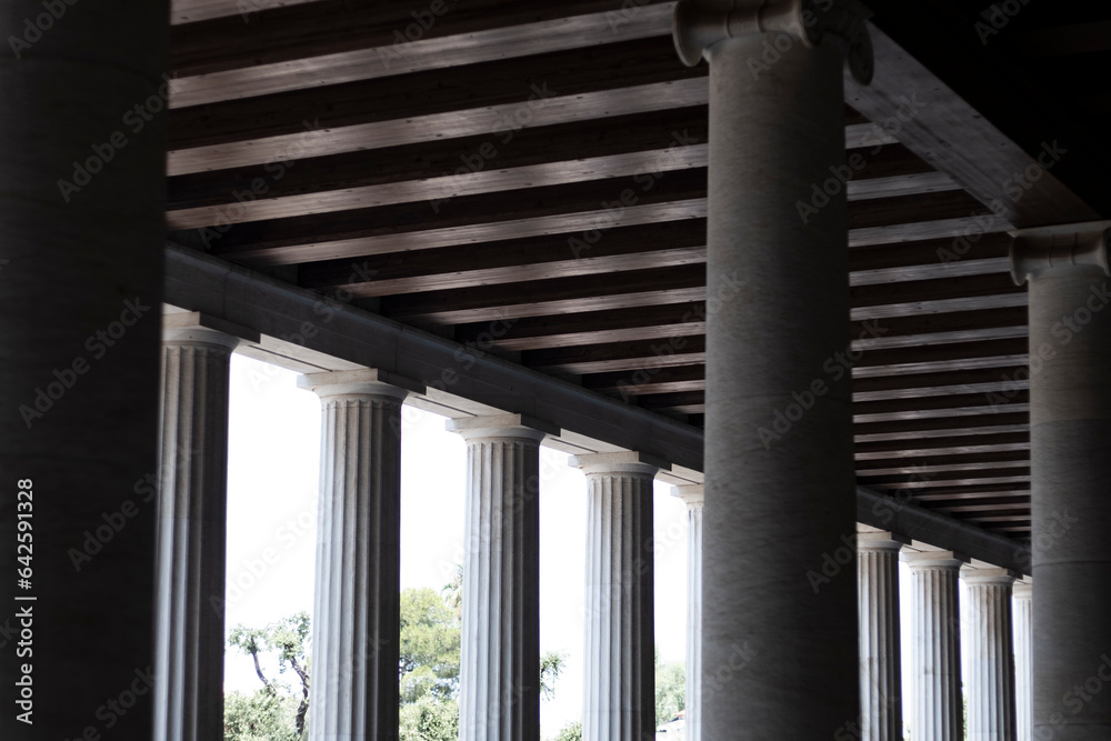 White ancient Greek columns in a row and wooden roof beams striped ...