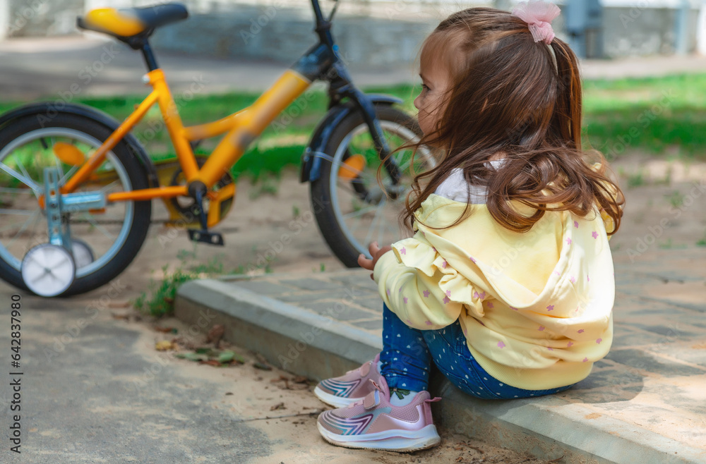 little girl fell off her bike and holds her bruised leg with her hands ...