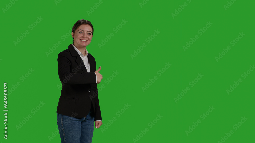 Side view of positive woman giving thumbs up over greenscreen backdrop ...
