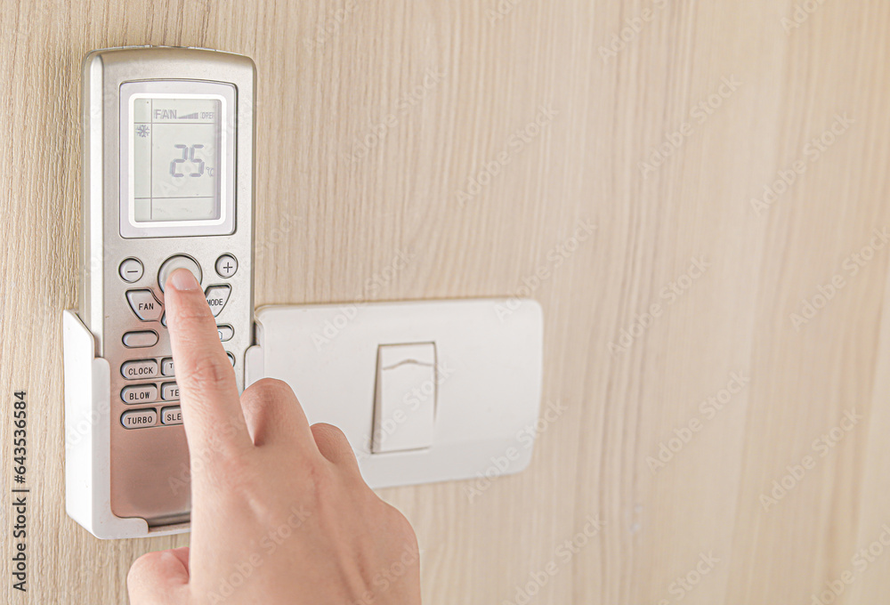 Female hand pressing air conditioner remote control to turn off. The ...